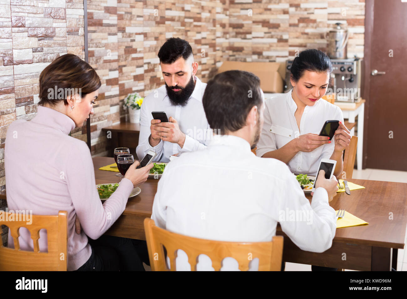 Group of people using smartphones at restaurant table and chatting ...