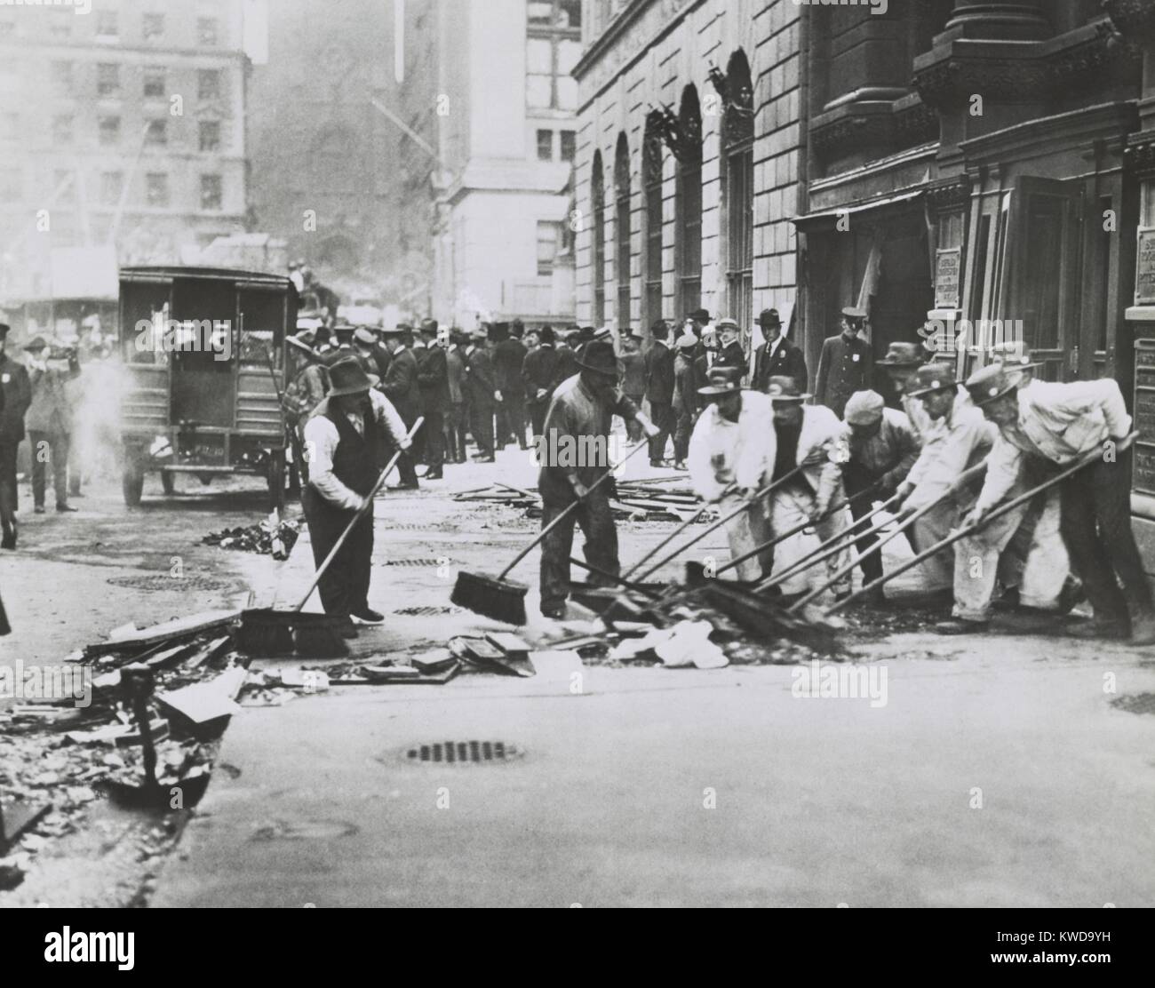 Workers sweeping up rubble and broken glass following Wall St. Bombing ...