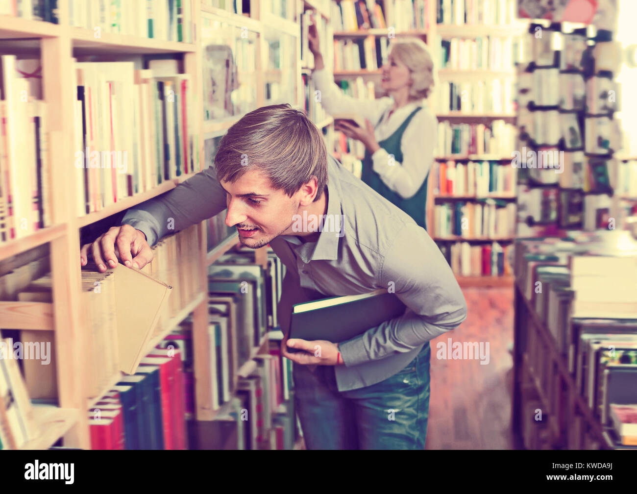 Man selecting book from bookshelf hi-res stock photography and images ...