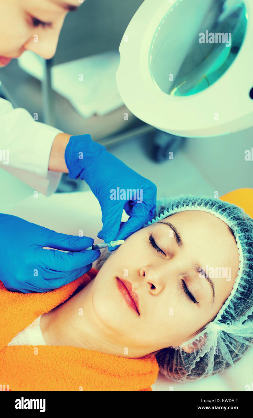 Glad positive female doctor doing beauty injection to young woman ...