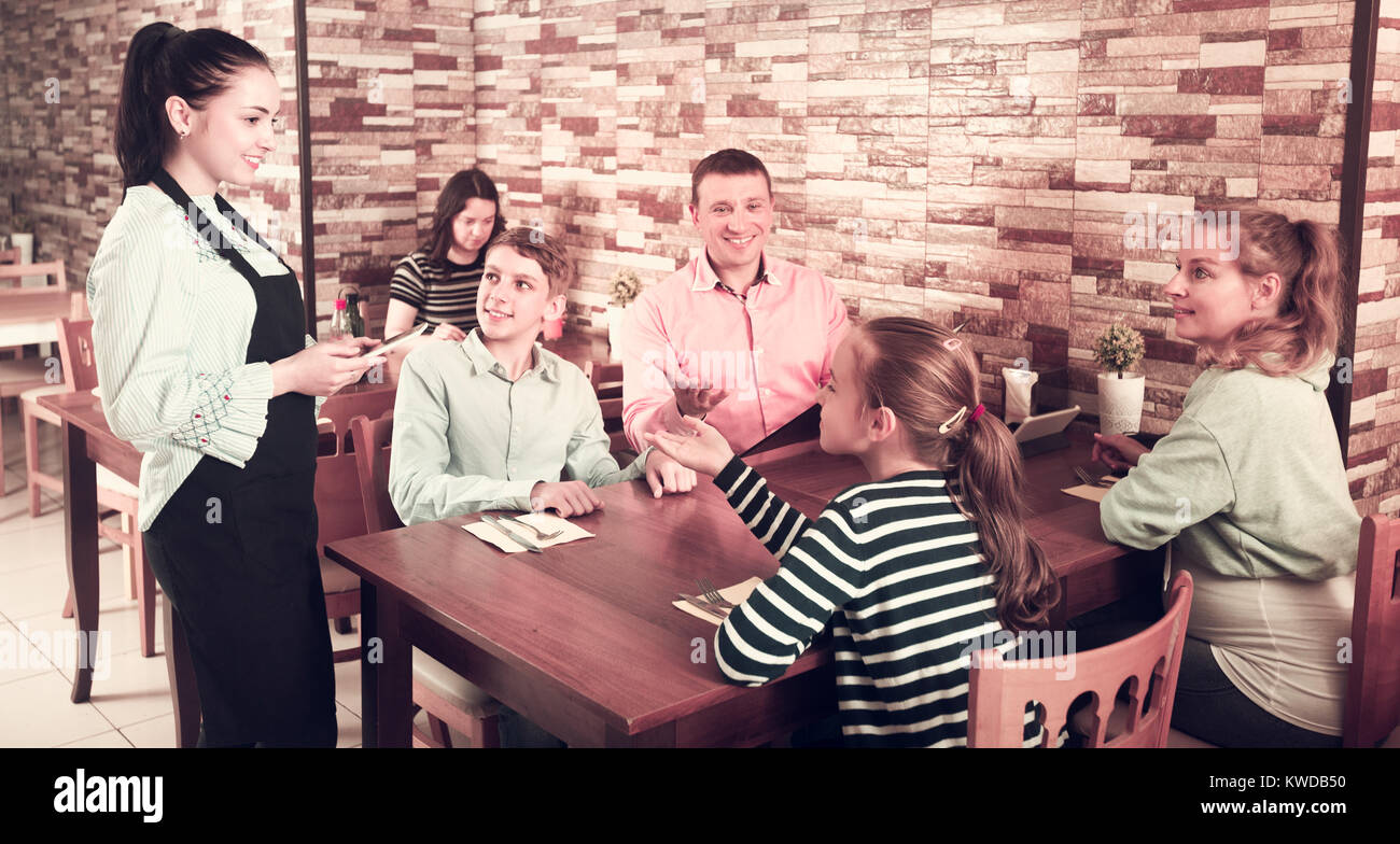 Young waitress taking order from guests and writing into note Stock ...