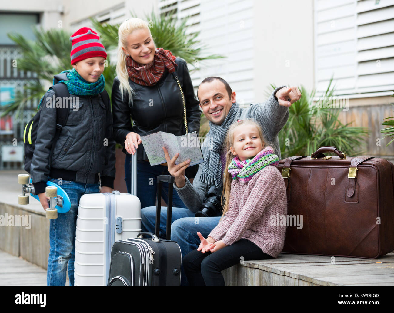 Happy middle class family of four checking direction in the city map ...