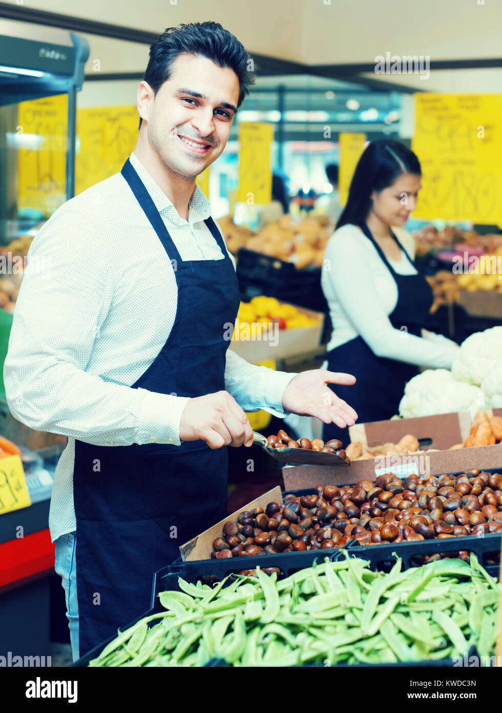 Happy sellers with Spanish chestnuts in market indoors Stock Photo - Alamy