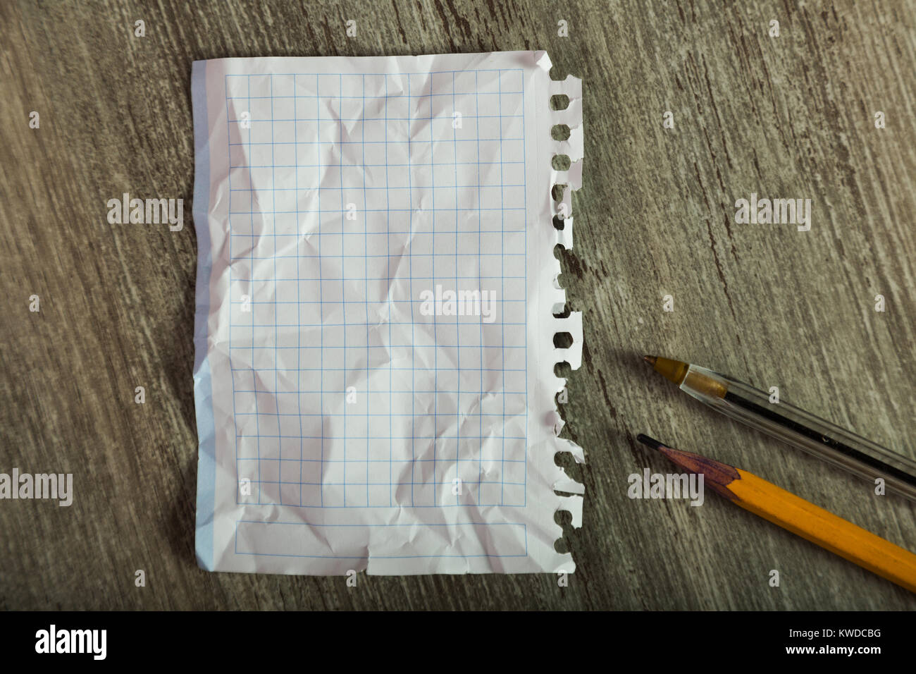 Crumpled notebook sheet in cage with pen and pencil Stock Photo - Alamy