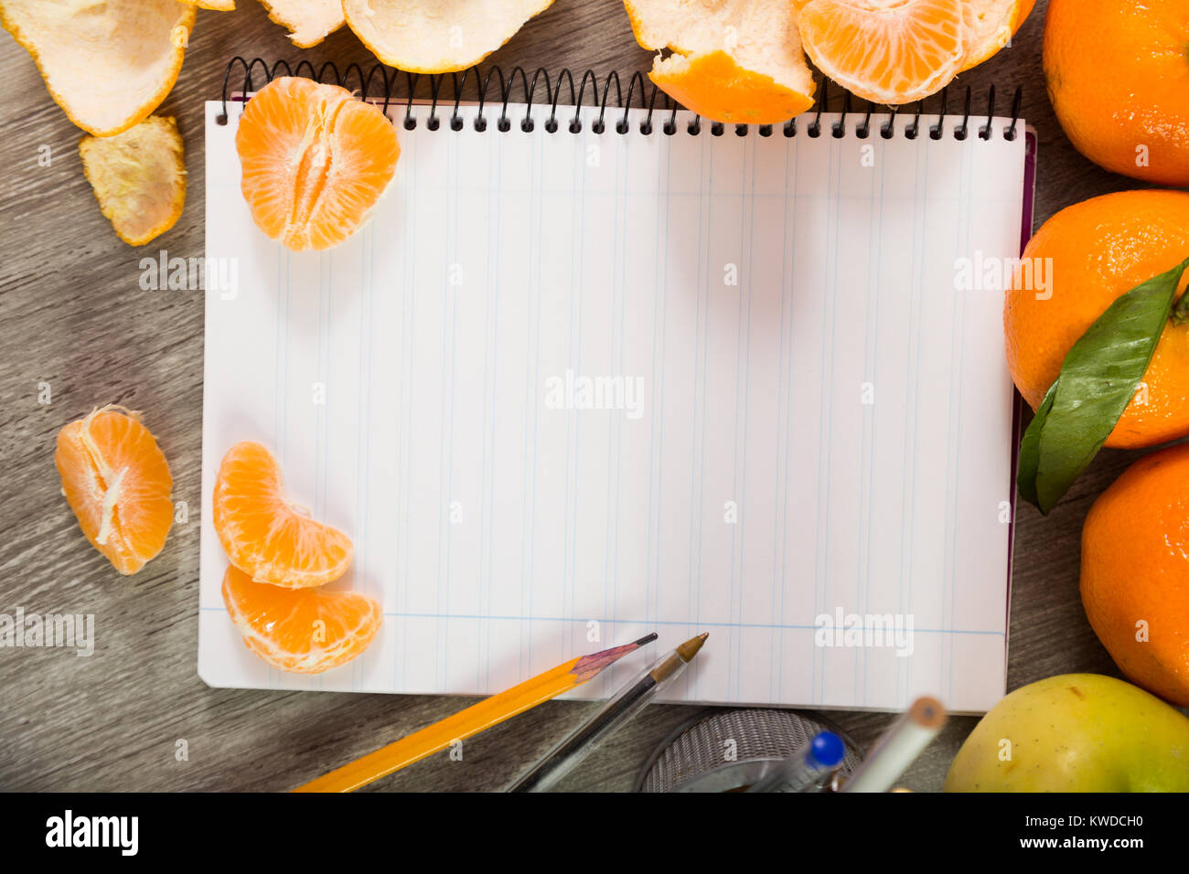 Notebook in range with writing utensils surrounded by fruit Stock Photo ...