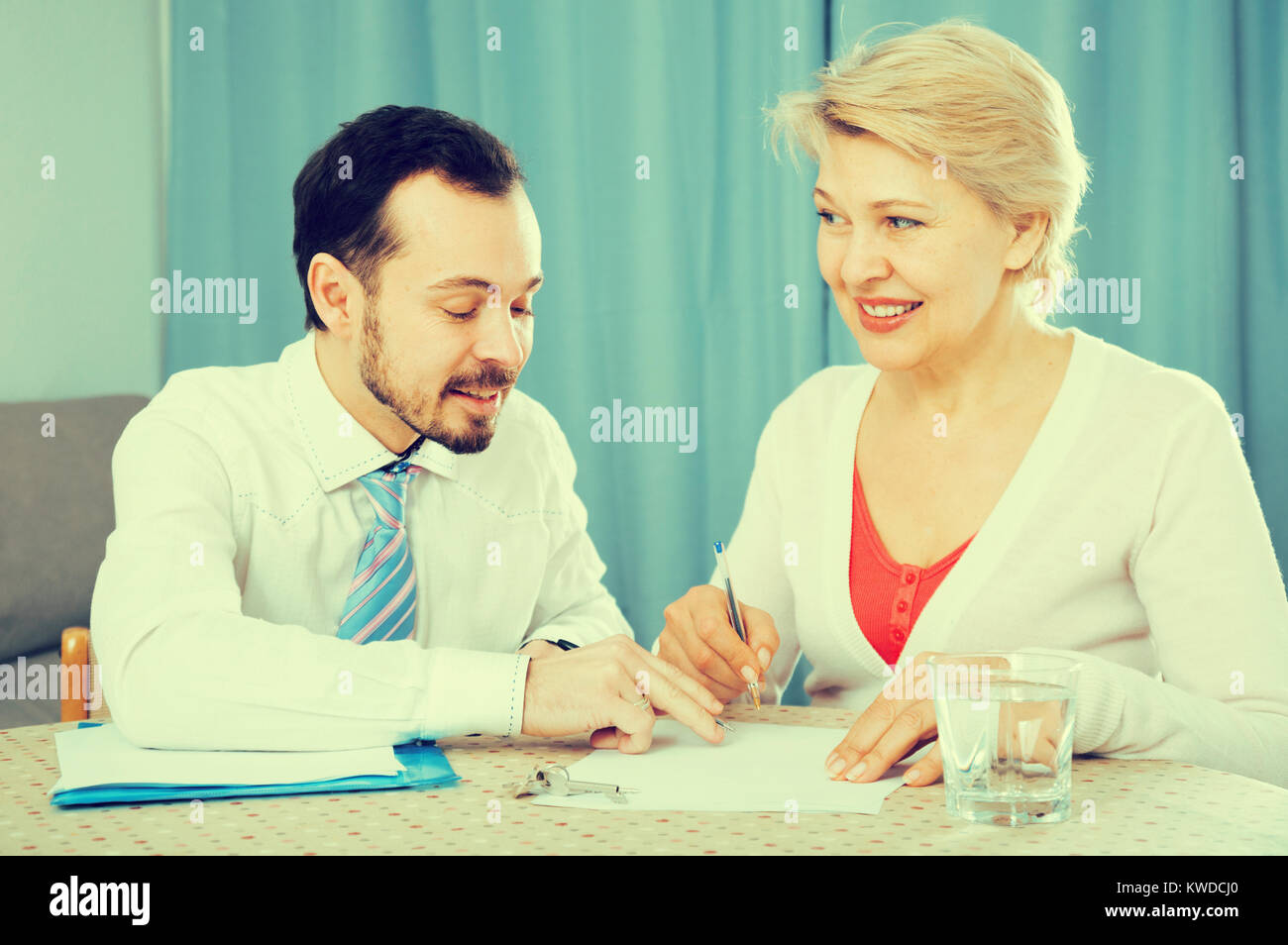 Mature woman and agent signing contract of rent apartments and hand ...