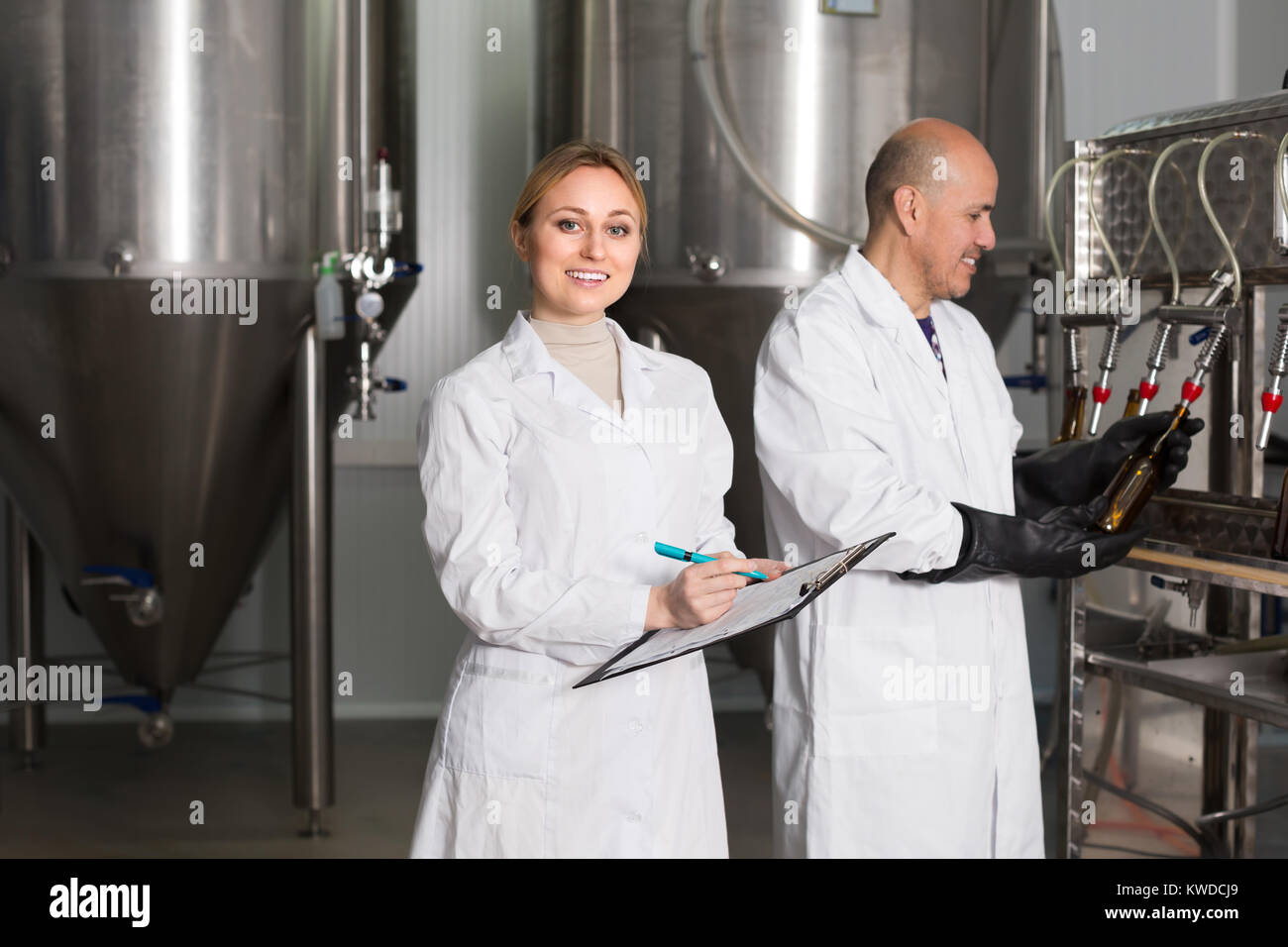 Portrait of two smiling workers in white uniform on beer brewery ...