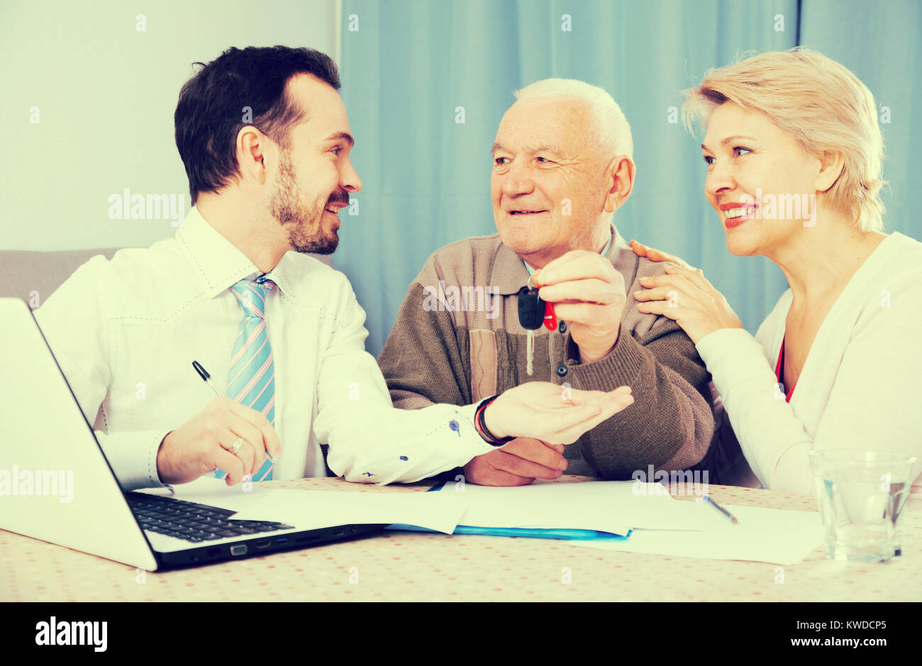 Old man and mature woman signing contract car lease and hand over keys ...