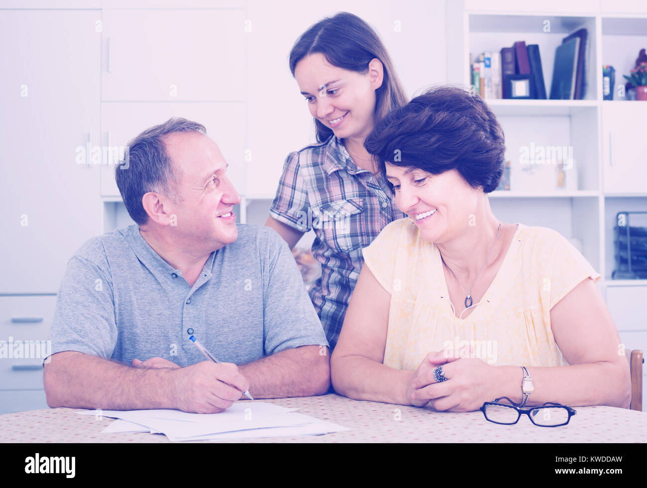Young woman daughter helping her senior parents to do paperwork at home ...