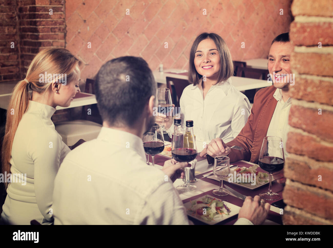 Group of glad cheerful people dining out merrily in country restaurant ...