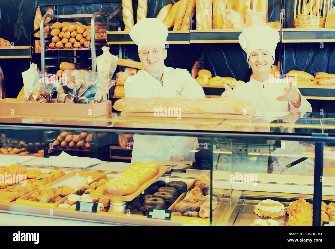 Portrait of cheerful bakers with fresh bread smiling in bakery Stock ...
