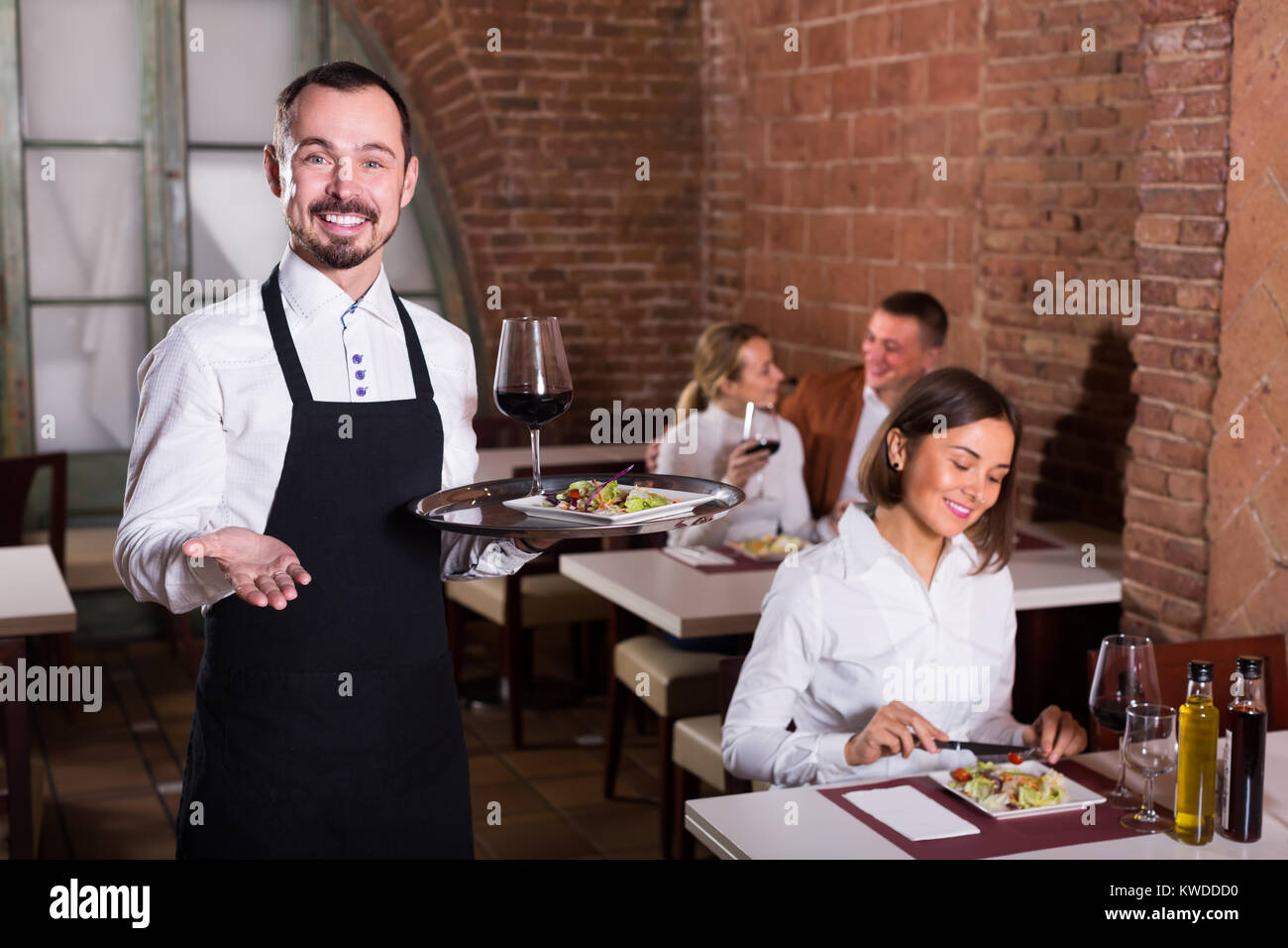 friendly man waiter demonstrating country restaurant to visitors Stock ...