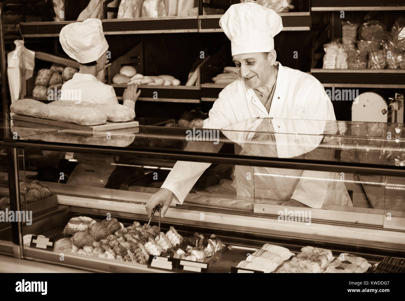 Mature male staff offering fresh cakes in sweet-shop Stock Photo - Alamy