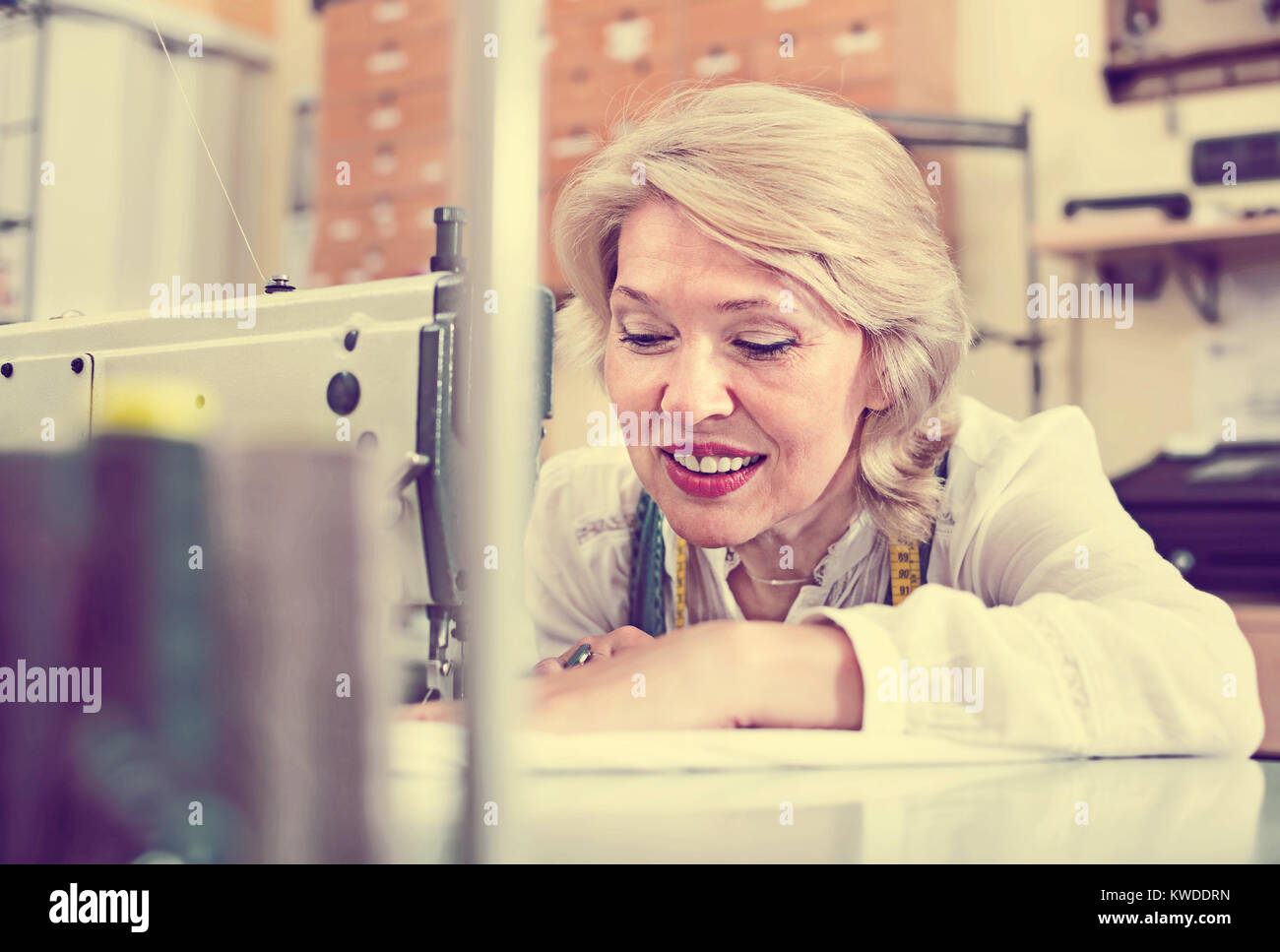 Portrait of professional female tailor working on a sewing machine in a ...