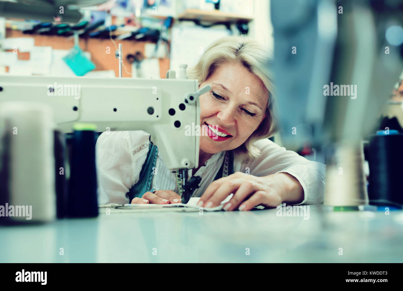 Portrait of professional female tailor working on a sewing machine in ...