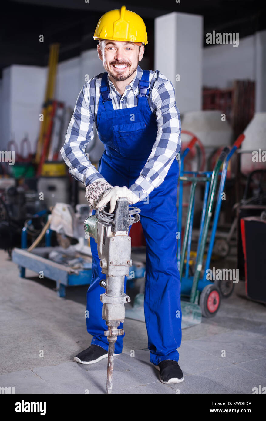 Smiling russian working man practicing his skills with pneumatic drill ...