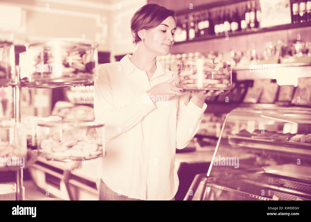 Female shop assistant demonstrating delicious rolled buns on tray in ...