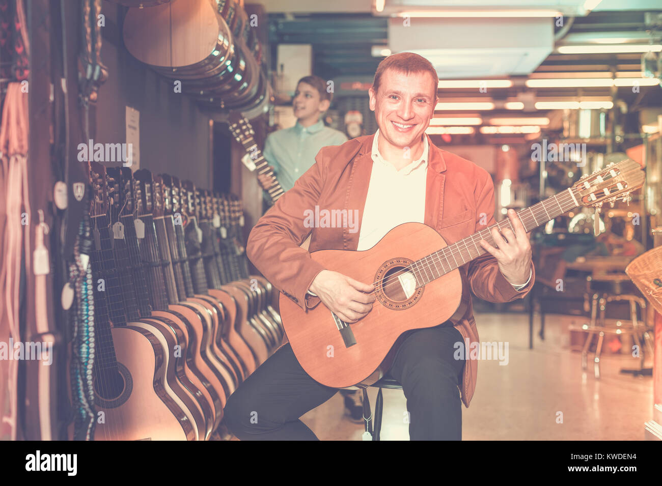 Smiling man demonstrates the possibilities of an acoustic guitar in a ...