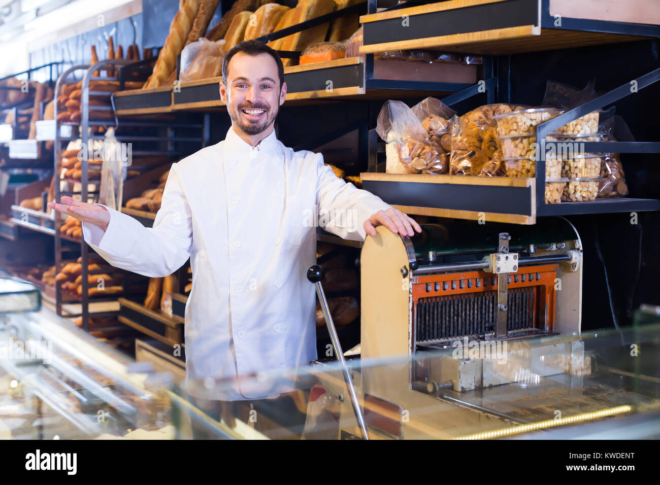 Optimistic male pastry maker demonstrating pastry in bakery Stock Photo ...