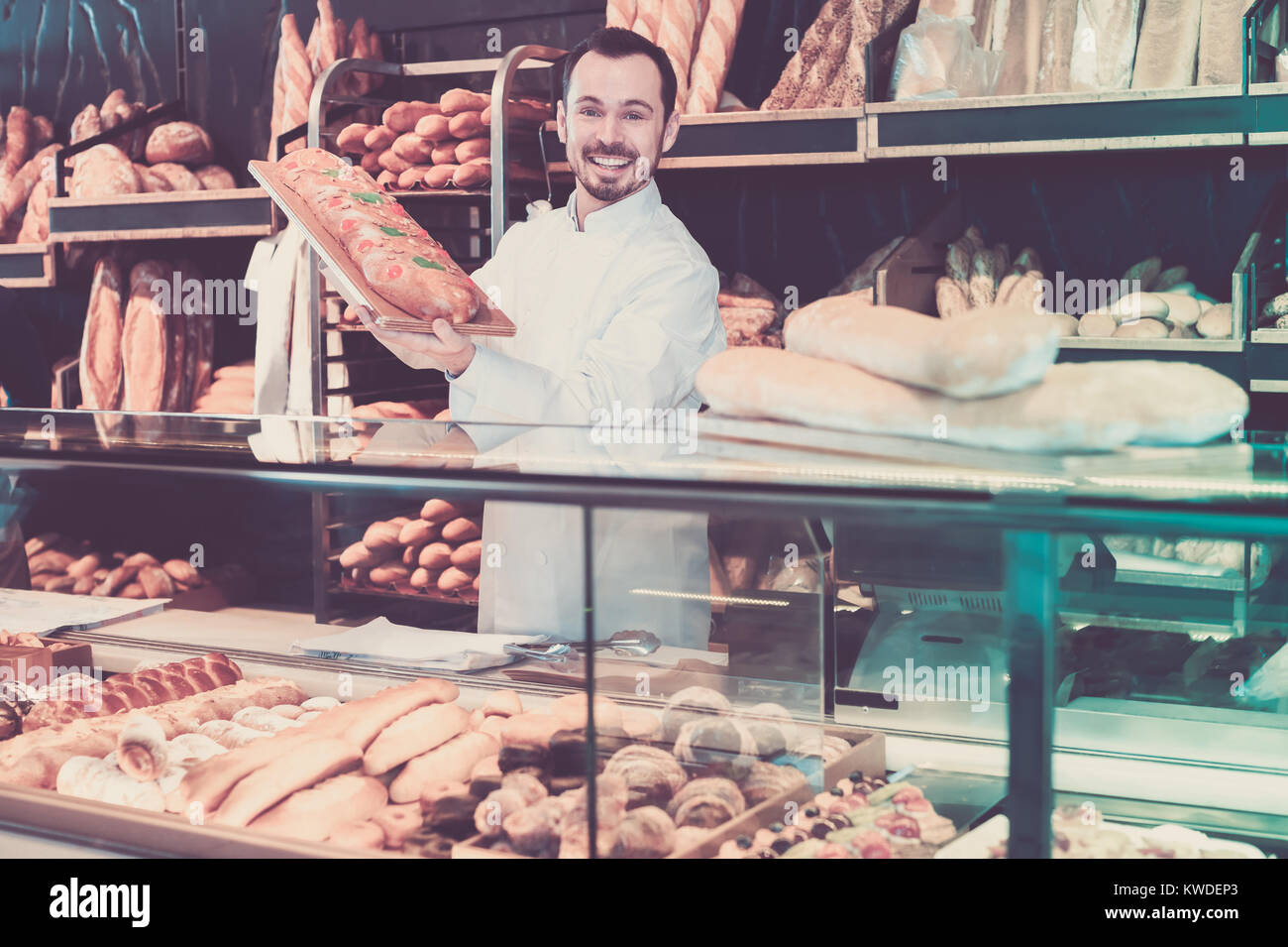 Smiling assistant demonstrating delicious festive cake in bakery Stock ...