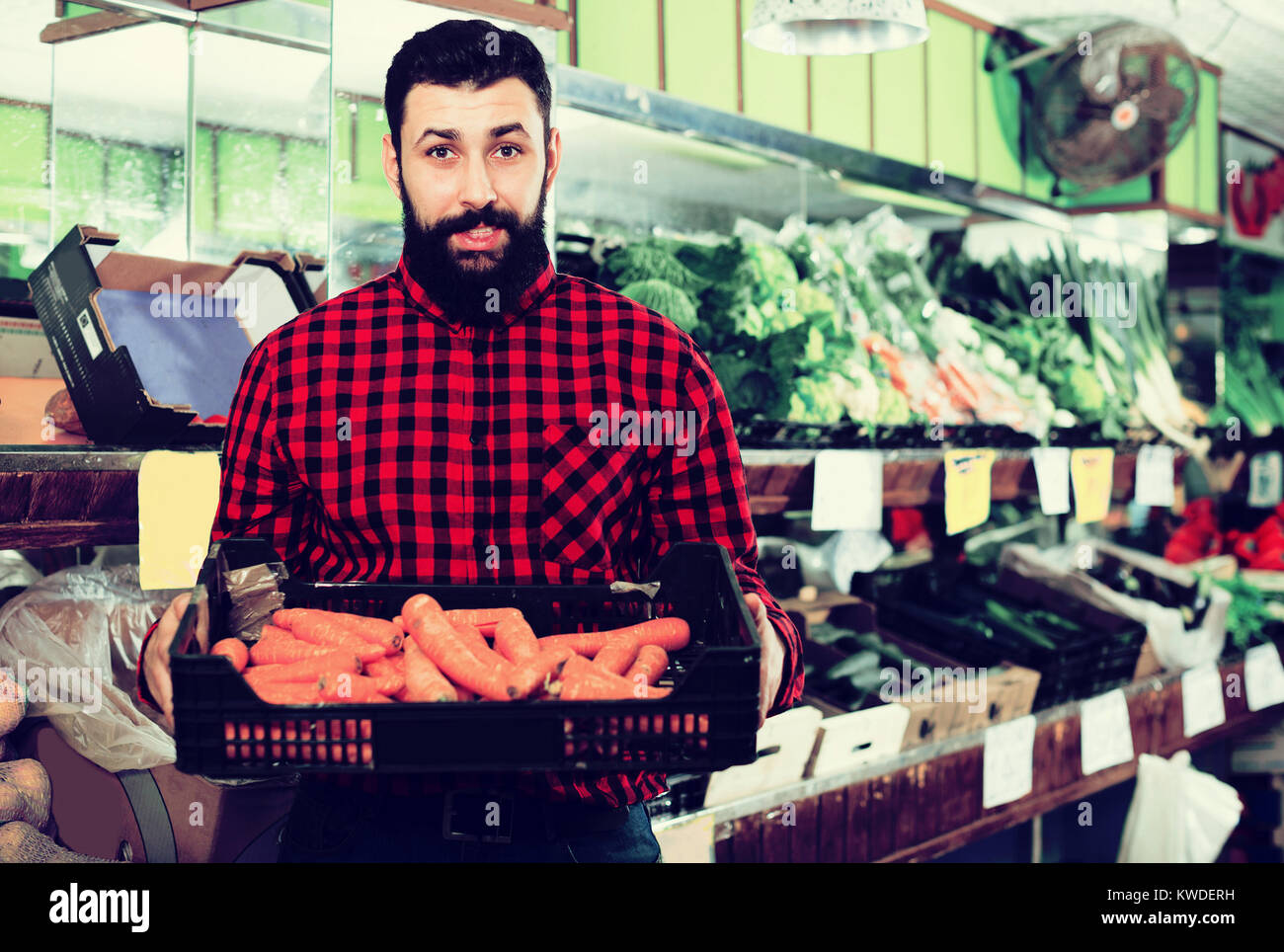 Male shop assistant demonstrating carrots in grocery shop Stock Photo ...