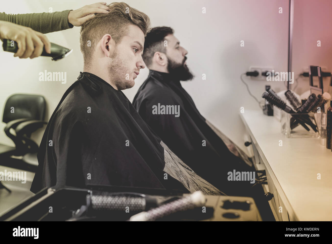 Young positive efficient clients having their hair cut by hairdressers ...