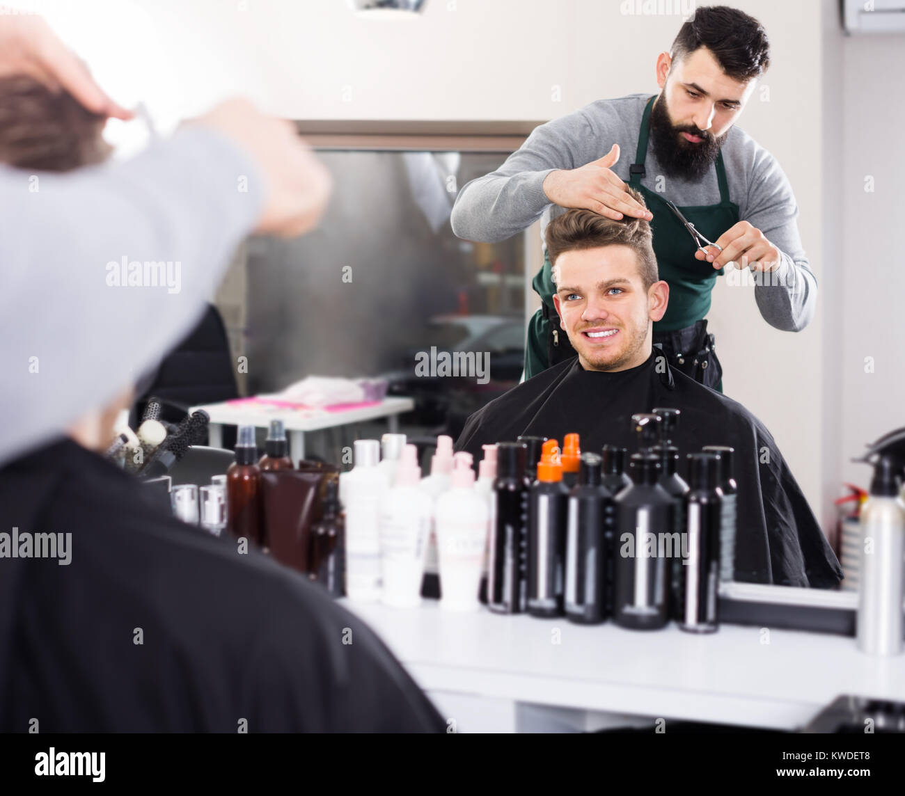 guy stylist creating new haircut for man client at hairdressing salon ...
