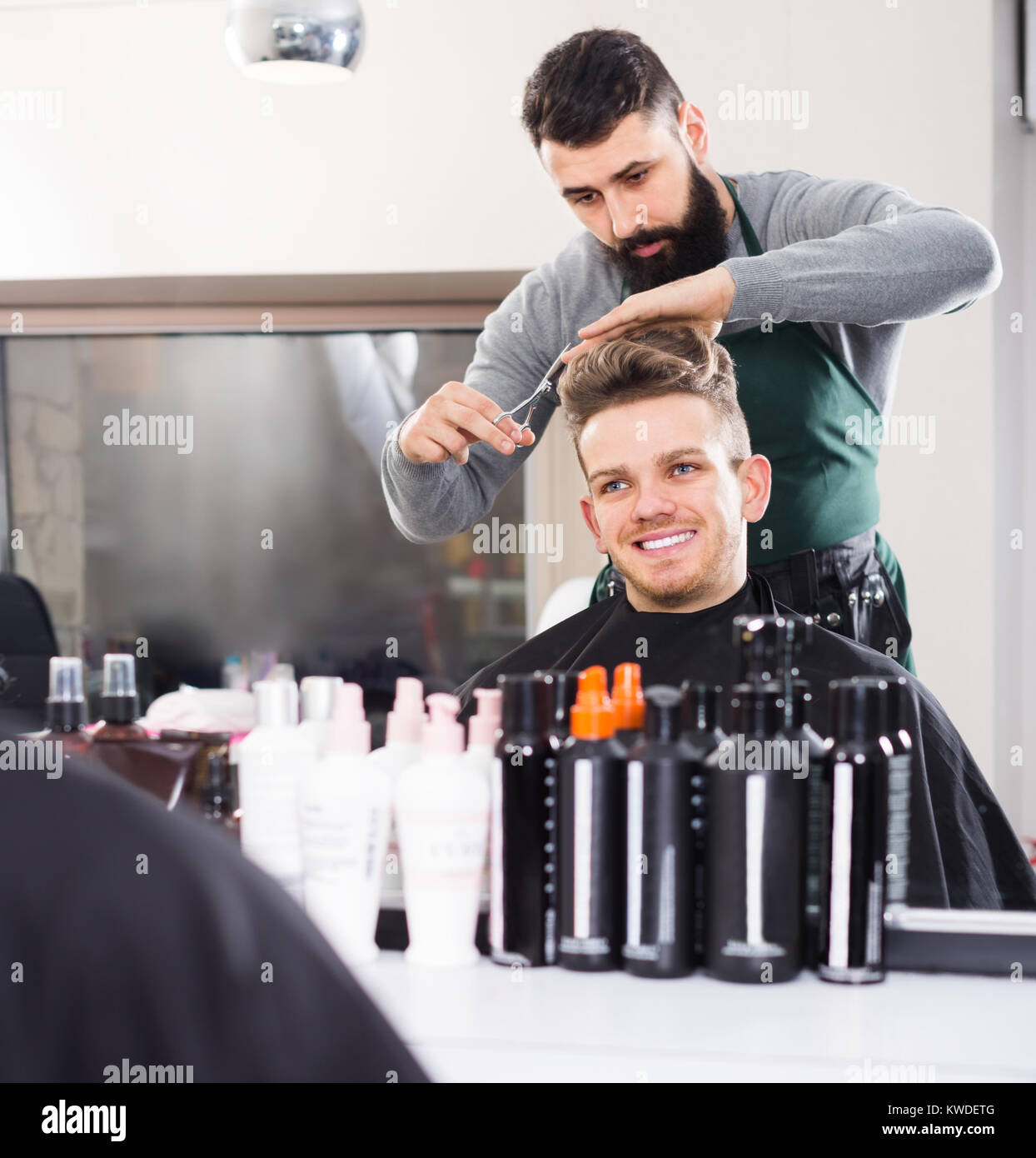 Young guy stylist creating new haircut for smiling man client at ...