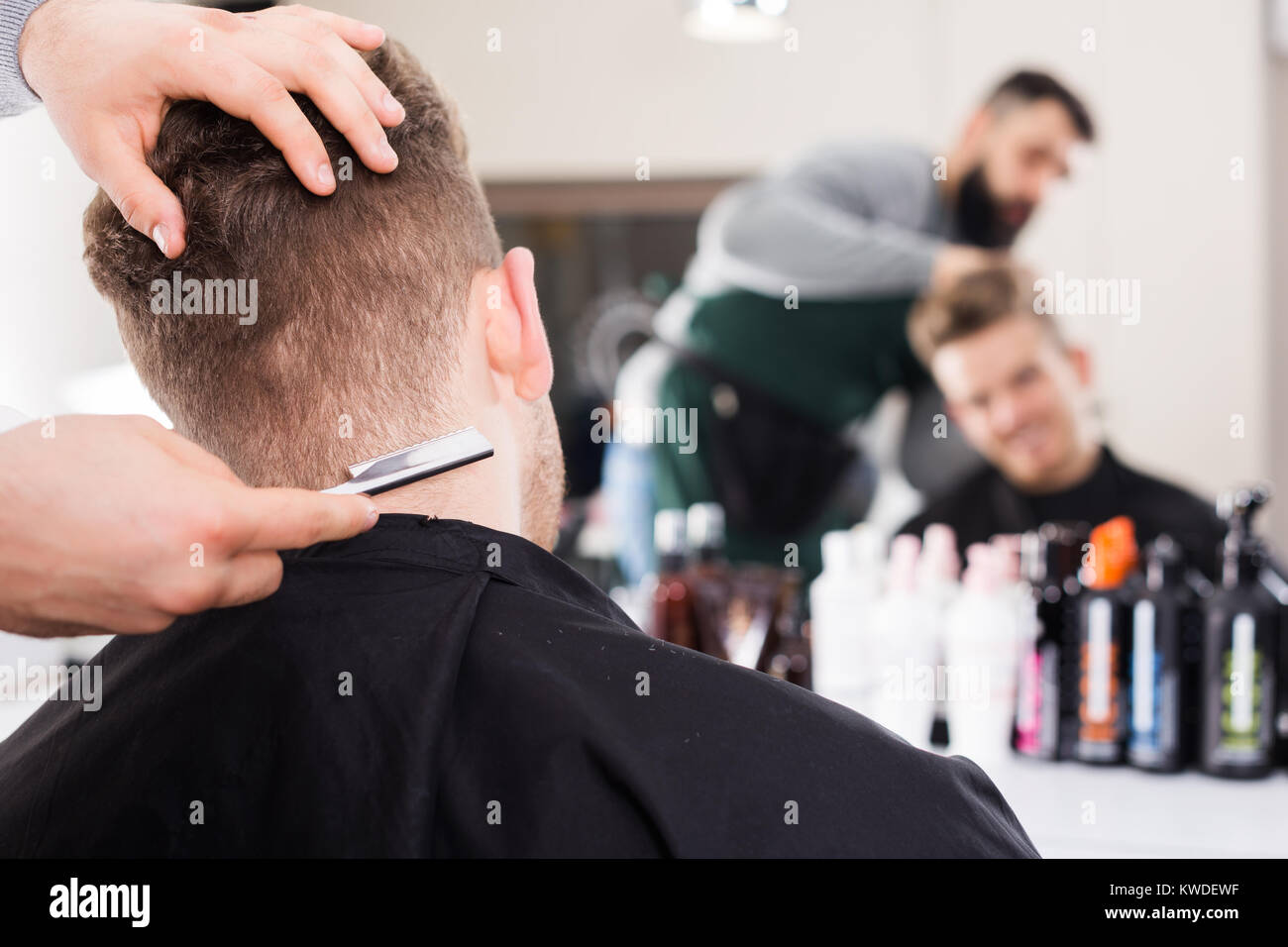 Positive man hairdresser doing new haircut for guy client at hair salon ...