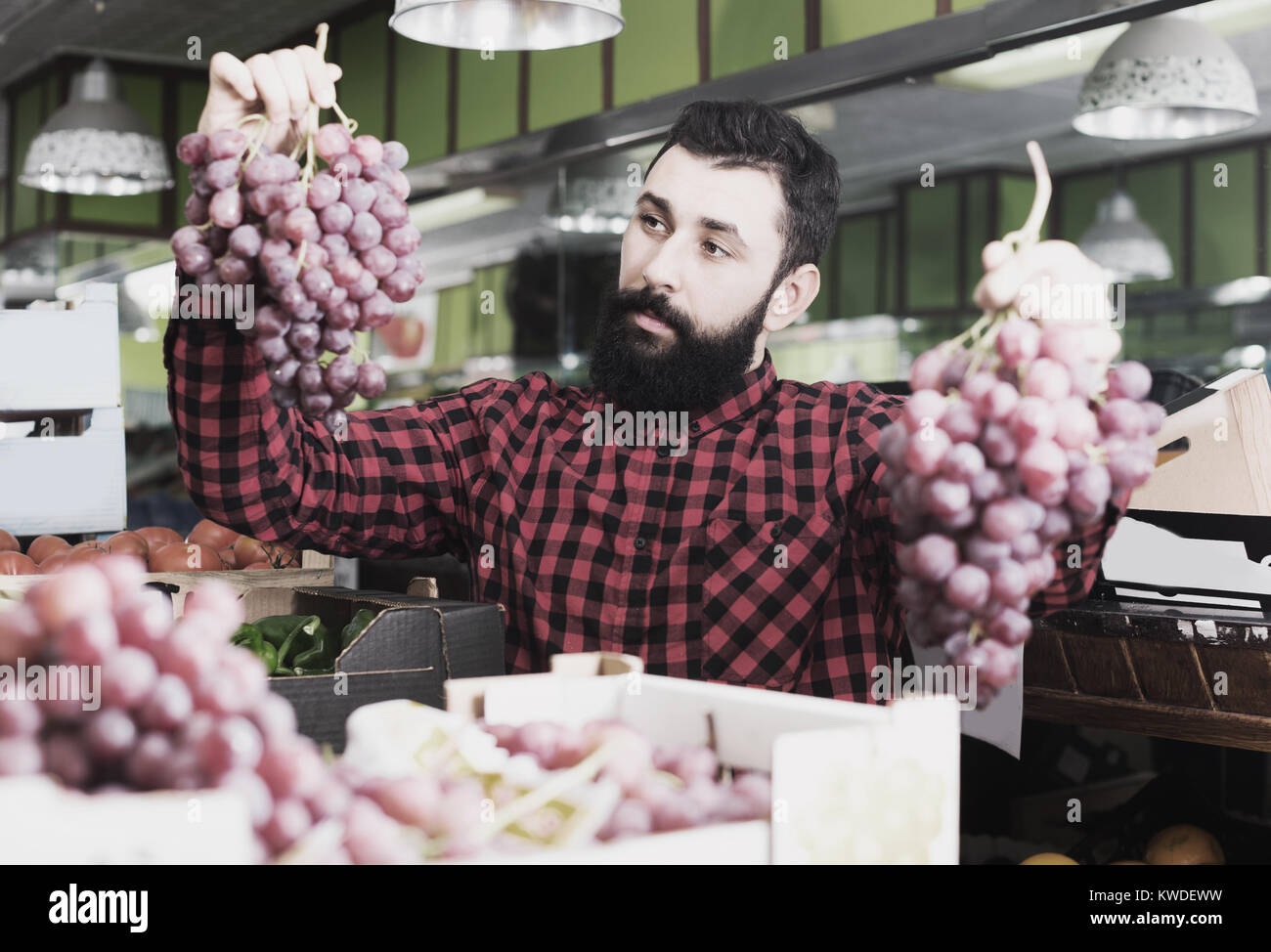 Shop assistant demonstrating grapes in grocery shop Stock Photo - Alamy