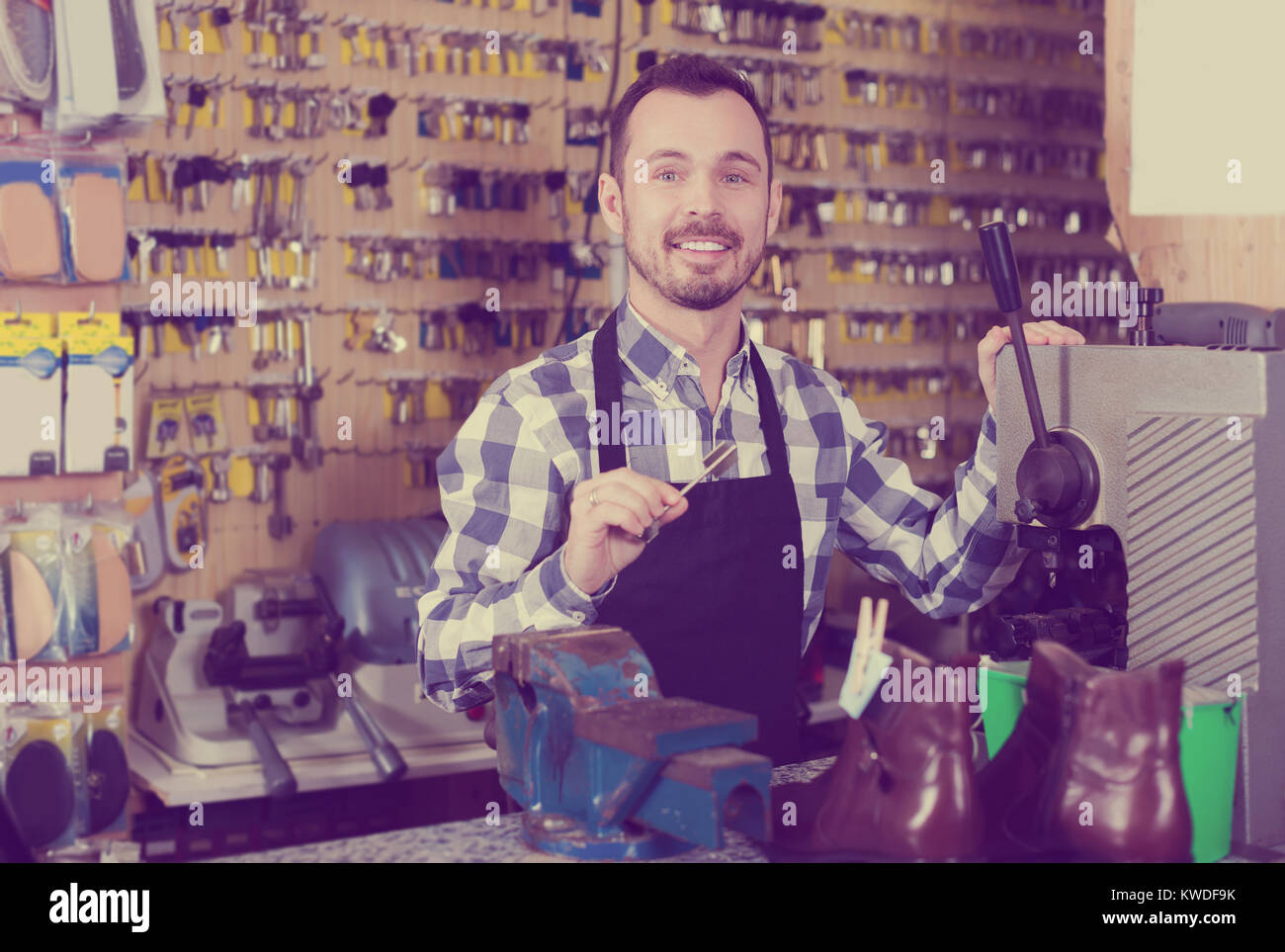 Young man worker demonstrating his tools for making keys in workshop ...