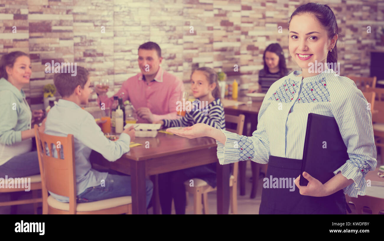 Gracious young waitress warmly welcoming guests to comfortable family ...