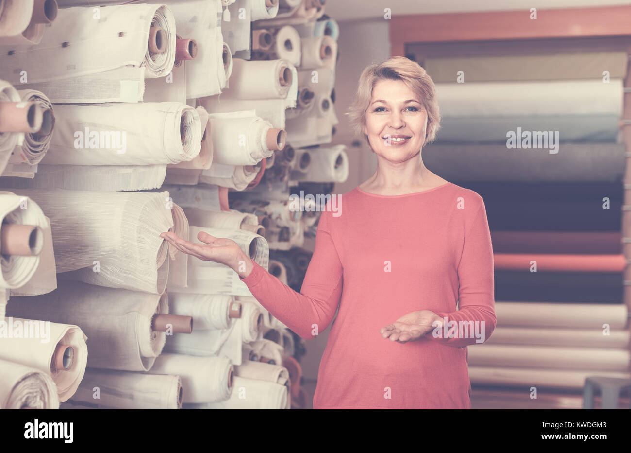 smiling english female shop assistant demonstrating assortment at ...