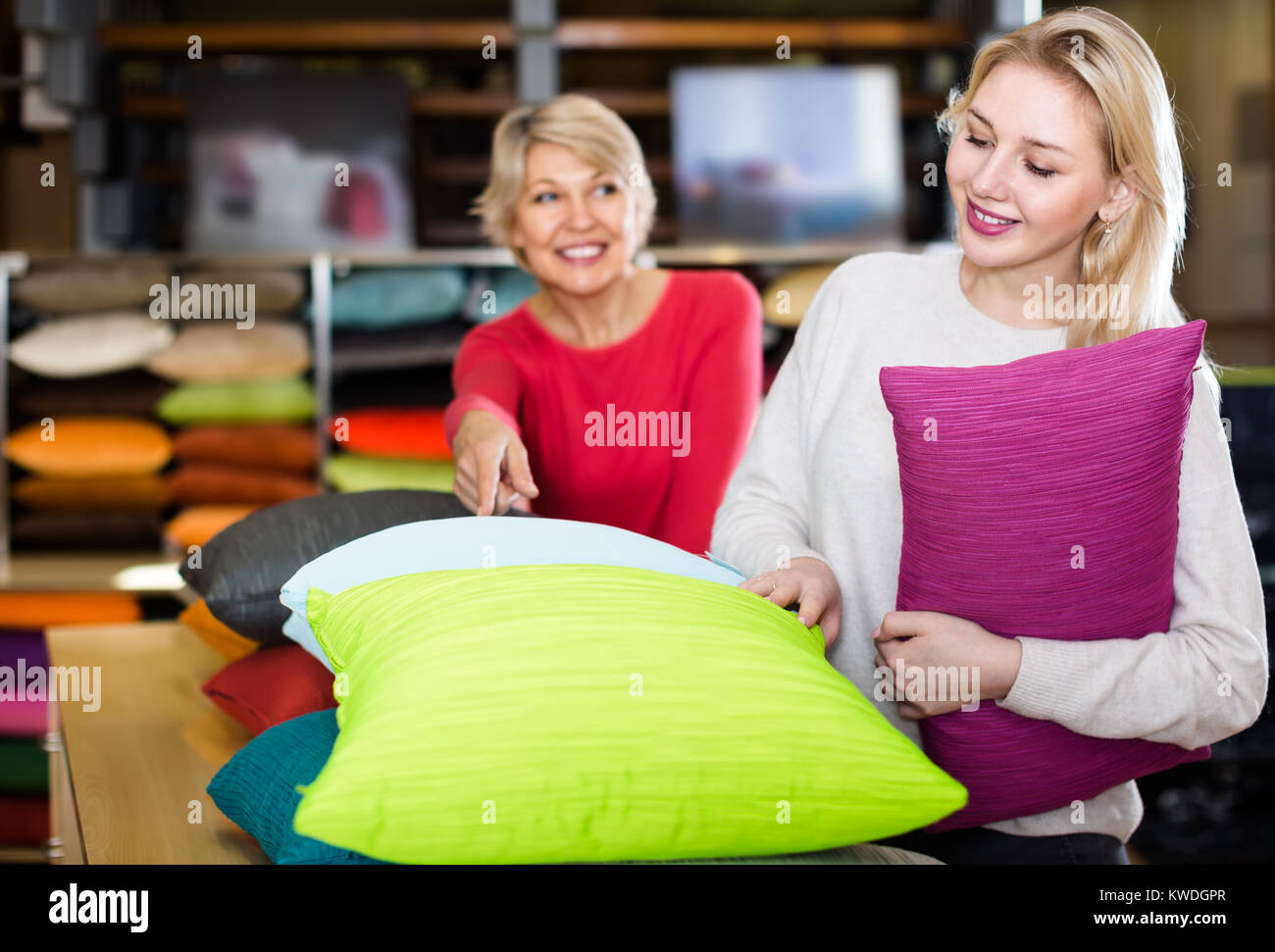 concentrated young and senior female customers looking through pillows ...