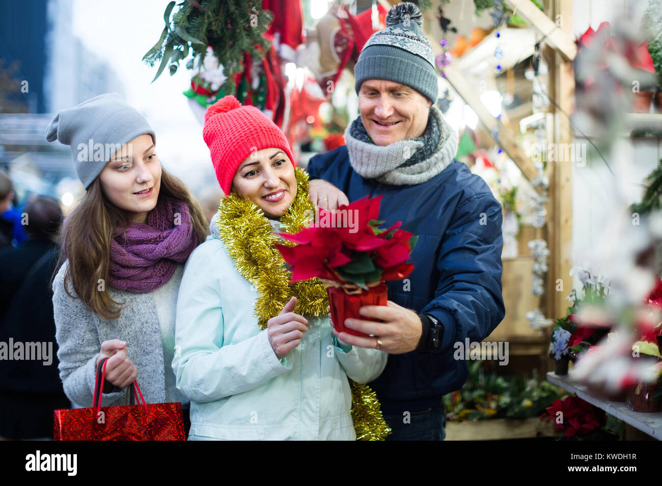 smiling spanish family of three with teenage girl choosing floral ...