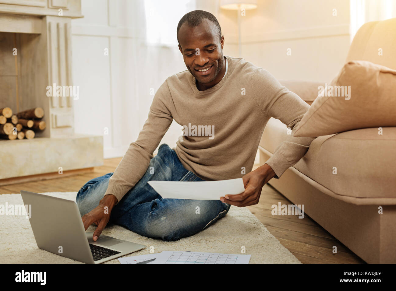 Smiling man sitting on the floor with paper Stock Photo - Alamy