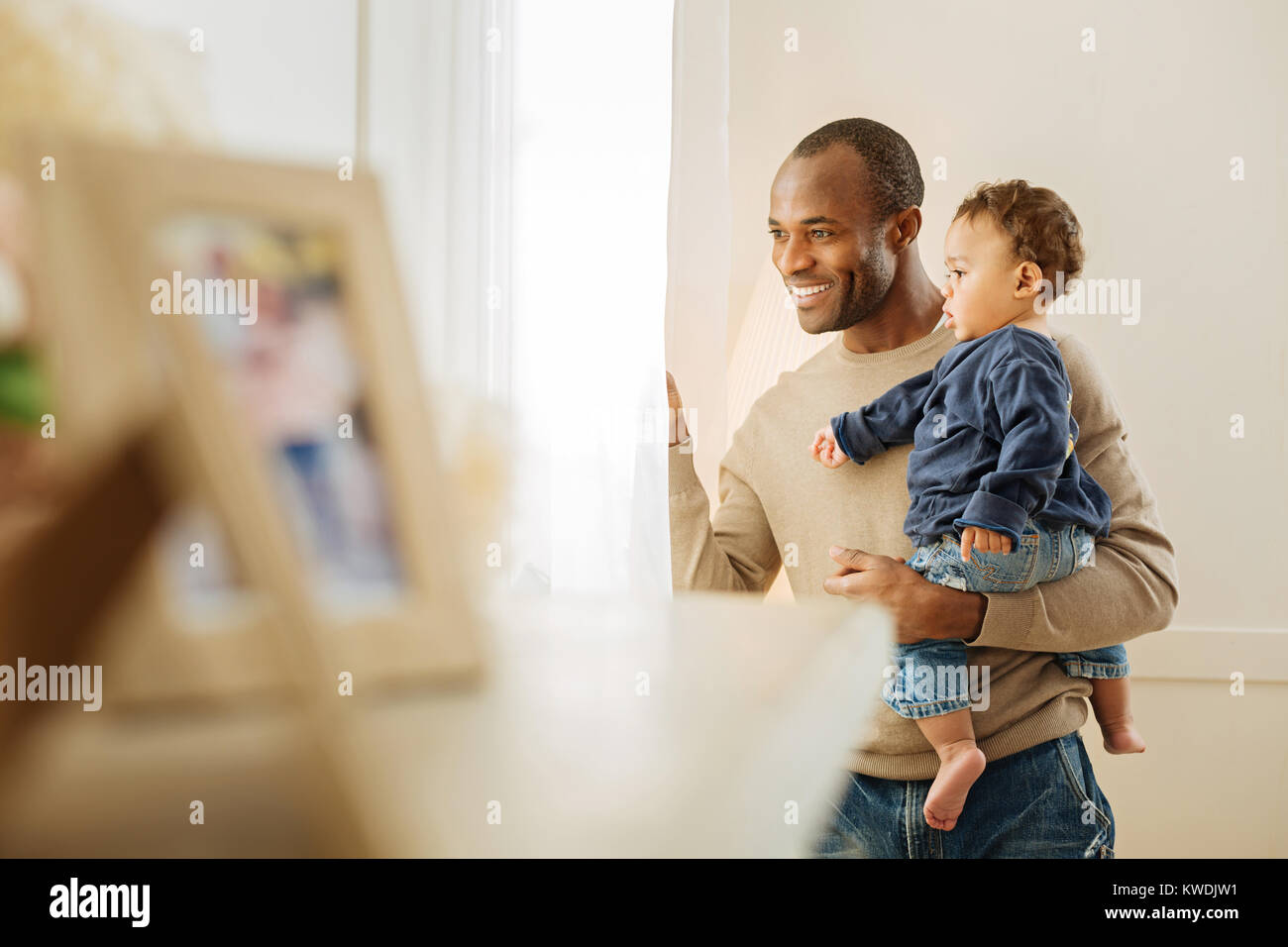 Alert man looking out the window with his son Stock Photo - Alamy