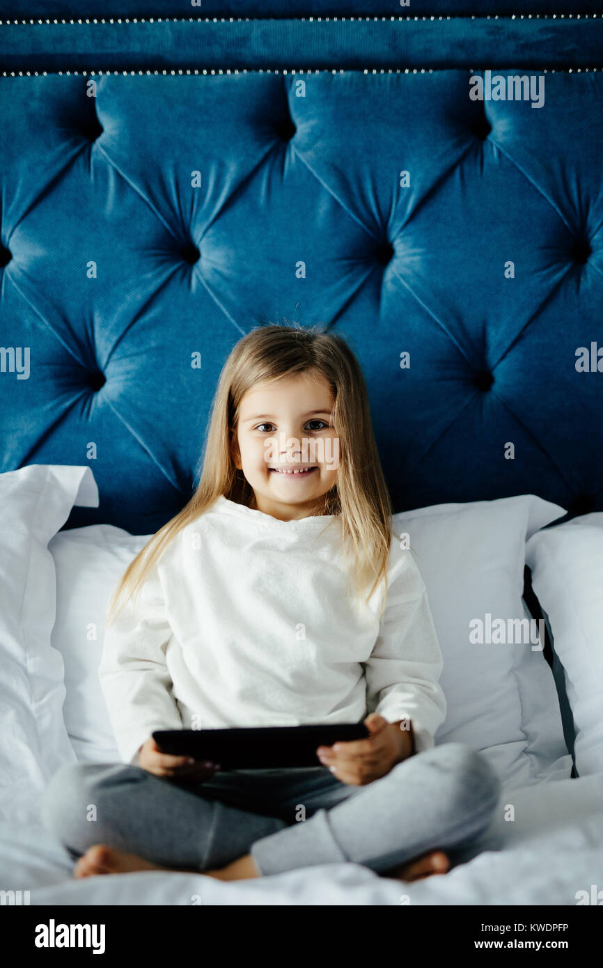 Cute girl using a tablet computer in her bedroom Stock Photo - Alamy