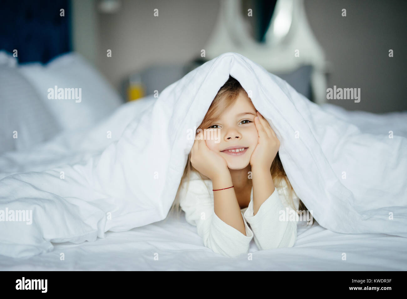 Pretty little girl in sleepwear lying under blanket Stock Photo - Alamy