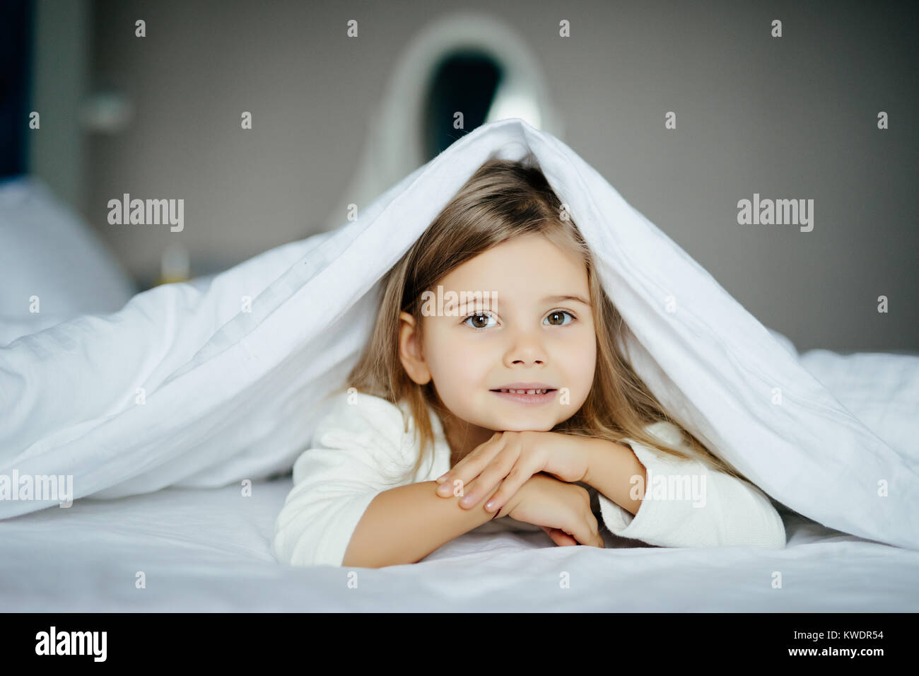 girl lying under a blanket in the bed and smiling Stock Photo - Alamy