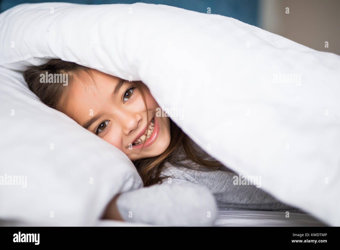 girl lying under a blanket in the bed and smiling Stock Photo - Alamy