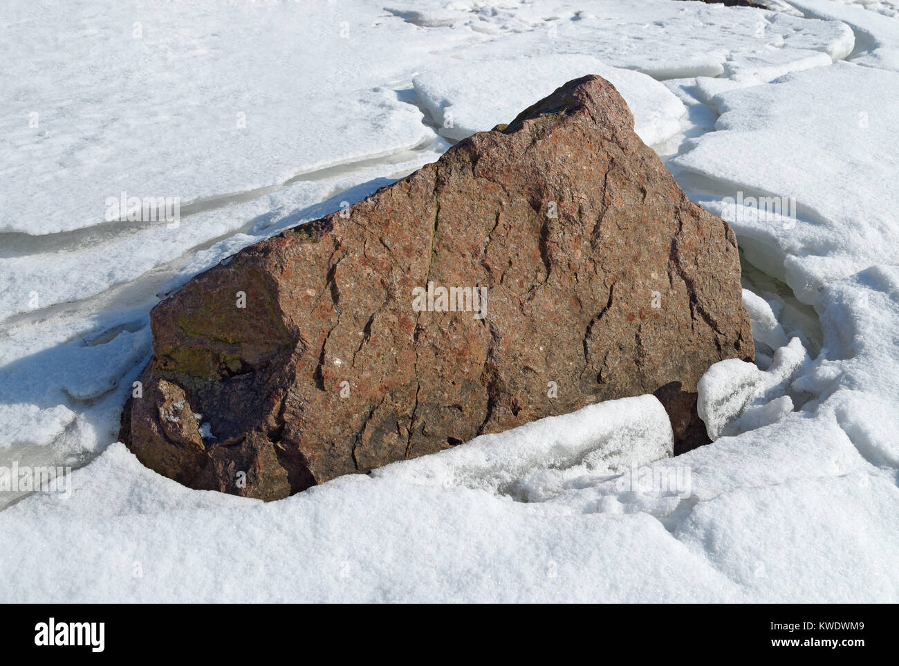 A large boulder in the snow.Has a rough texture the brown color Stock ...
