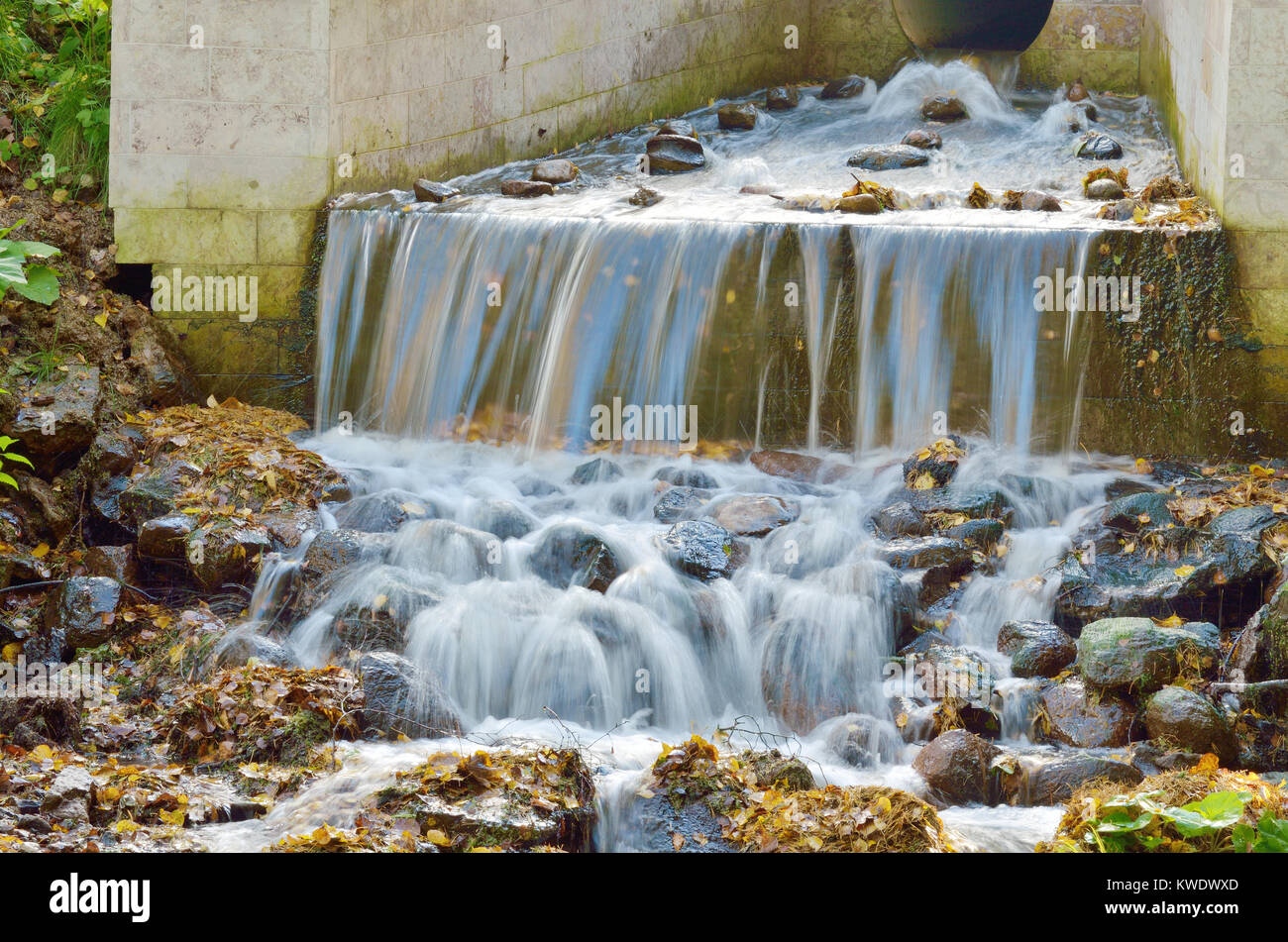 The river flows under the bridge through the tube Stock Photo - Alamy
