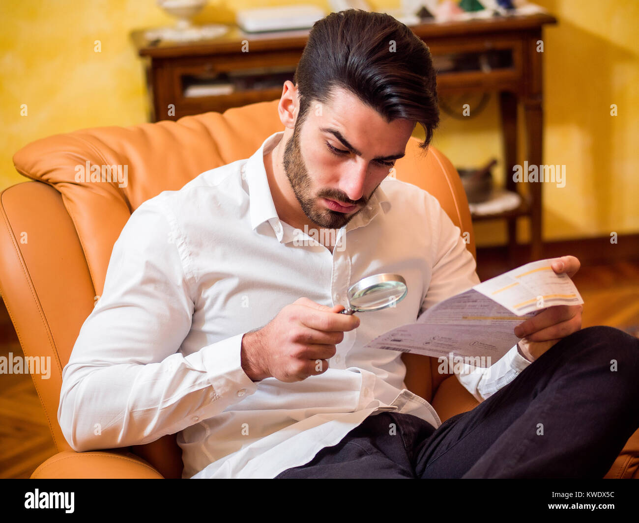 Young Man Sitting at Desk Scrutinizing Paper Contract with Magnifying ...