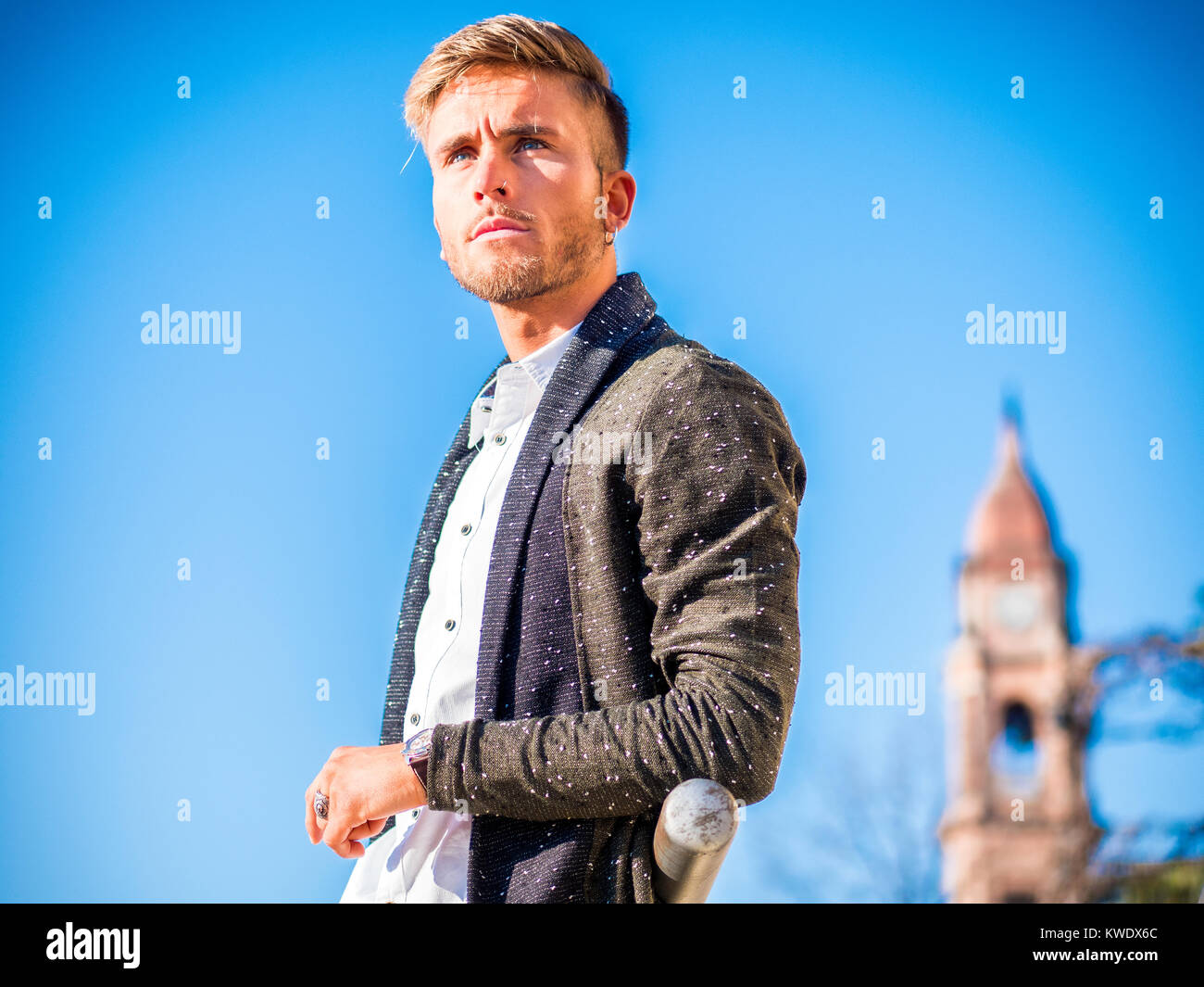 Handsome trendy blond man standing outdoor in European city setting ...