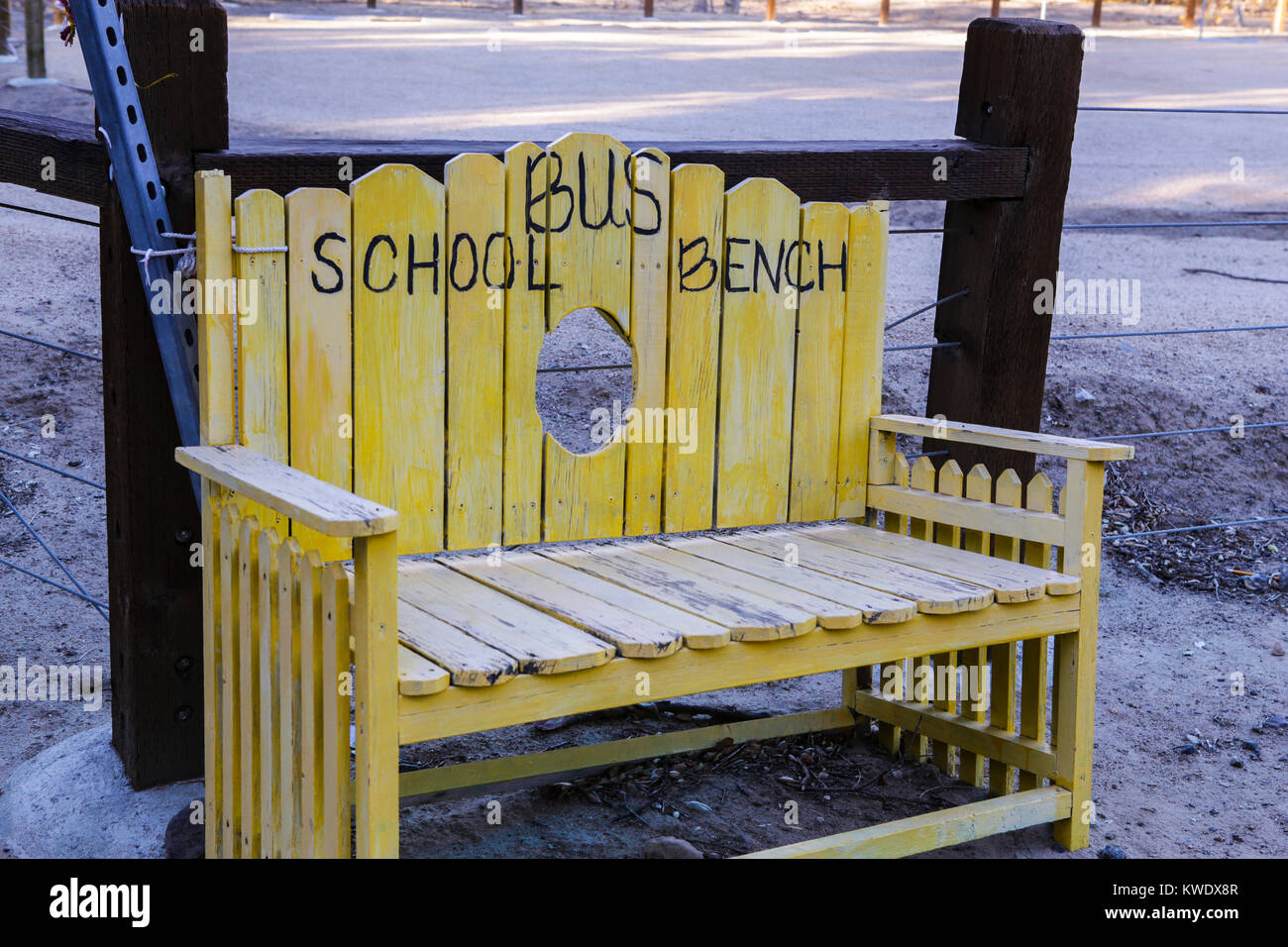 A yellow wooden school bus stop bench in a rural southern California ...