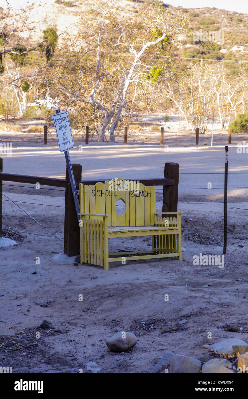 A yellow wooden school bus stop bench in a rural southern California ...