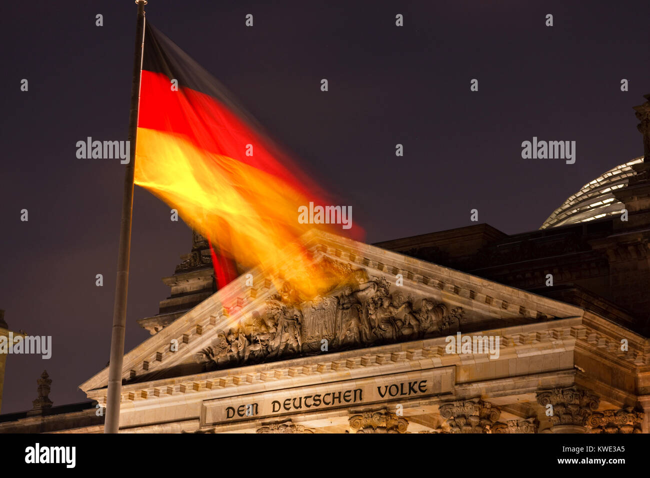 A german flag in front of the Reichstag building in Berlin at night ...