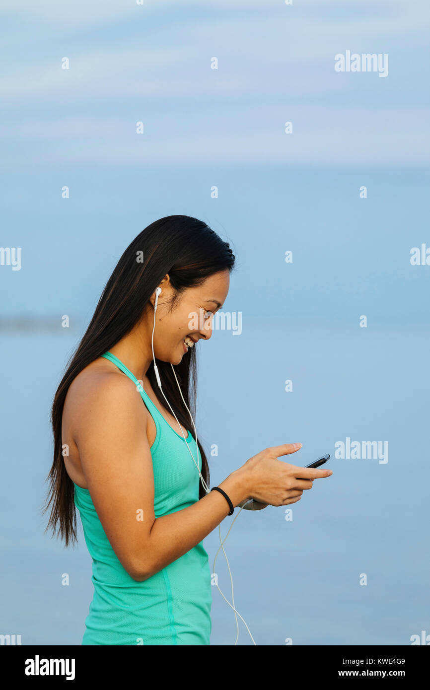 Happy woman listening music while using smart phone Stock Photo - Alamy