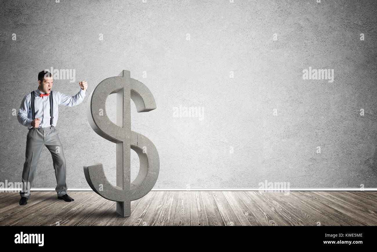 Determined banker man in empty concrete room breaking dollar figure ...